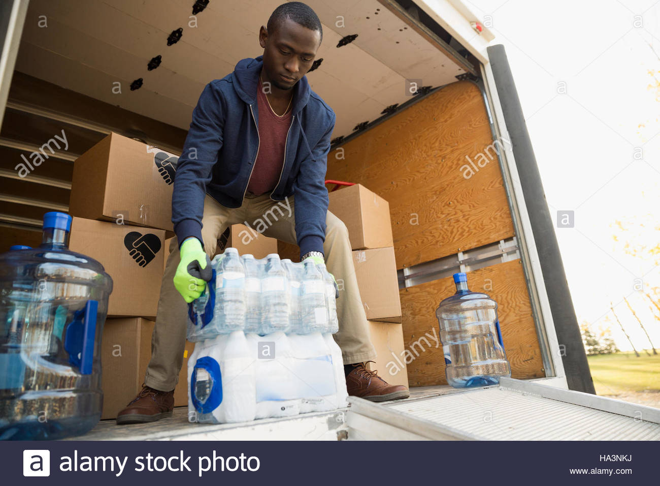 Volunteer unloading water bottle cases on truck Stock Photo - Alamy