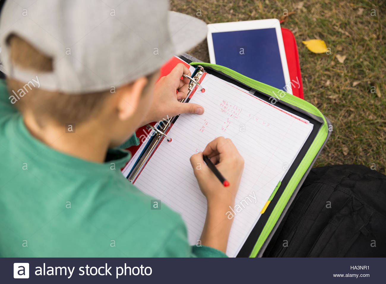 Tween boy doing homework in grass Stock Photo - Alamy