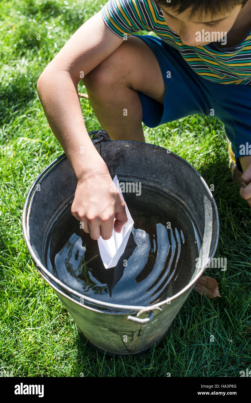 Child play with boat in a bucket of water Stock Photo - Alamy