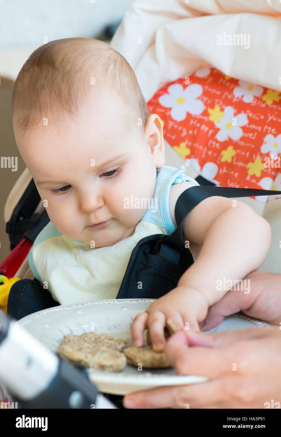 Baby eats alone. Eating homemade biscuits Stock Photo - Alamy