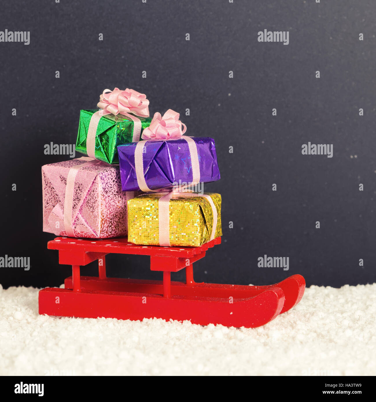 red festive sled with full gift boxes in snow on chalkboard background ...