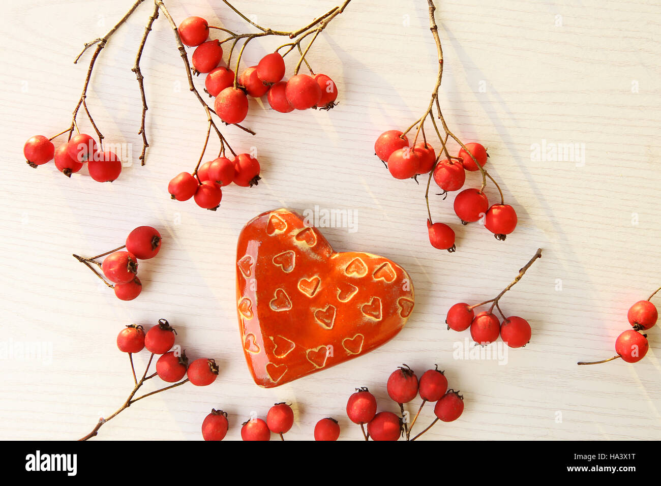 Ceramic heart and hawthorn berries on white wooden background. Top view ...