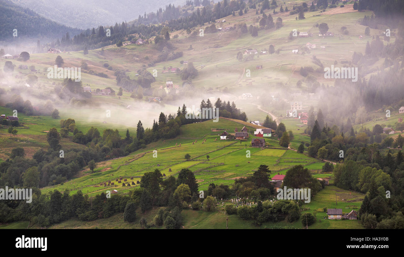 Alpine village in mountains. Smoke and haze over the hills in ...
