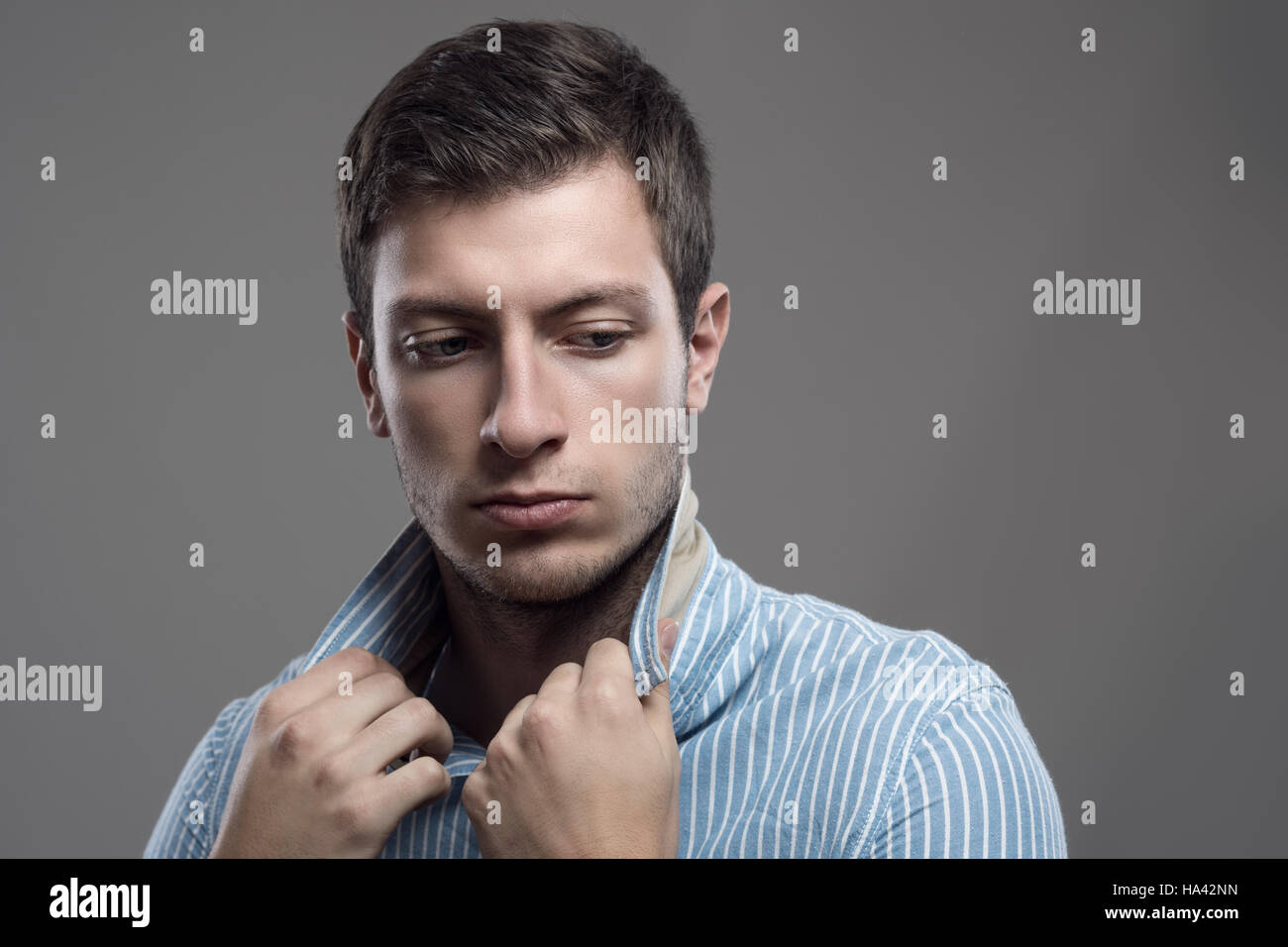 Intense moody portrait of young stubble man holding collar looking ...