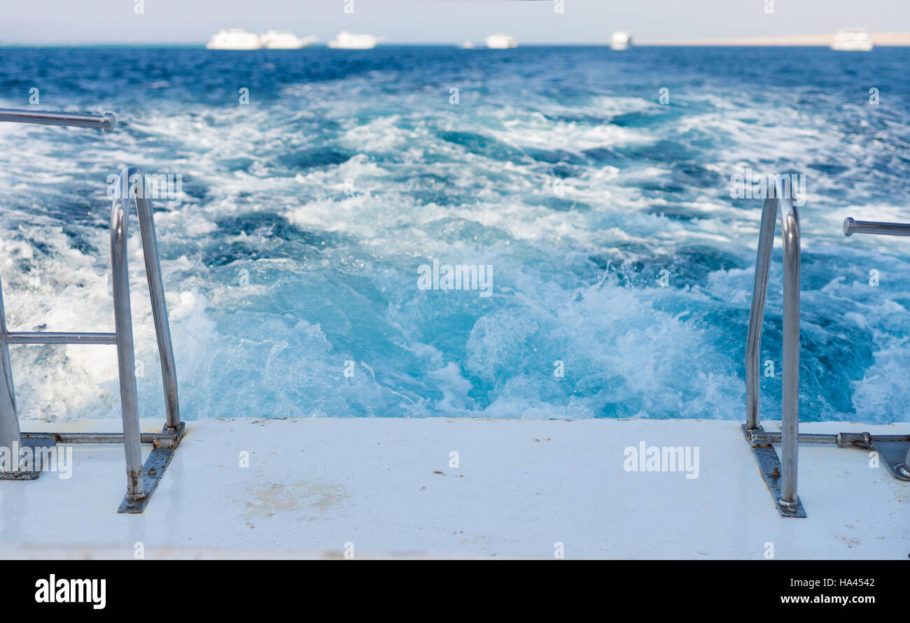 View of a ship's wave wake between metal steel ladders on back teak ...