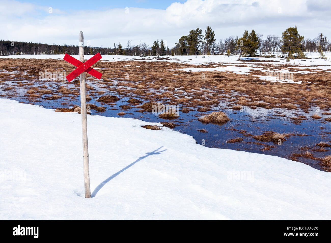Closeup on a Snowmobile sign, red cross and trail in springtime. Snow ...