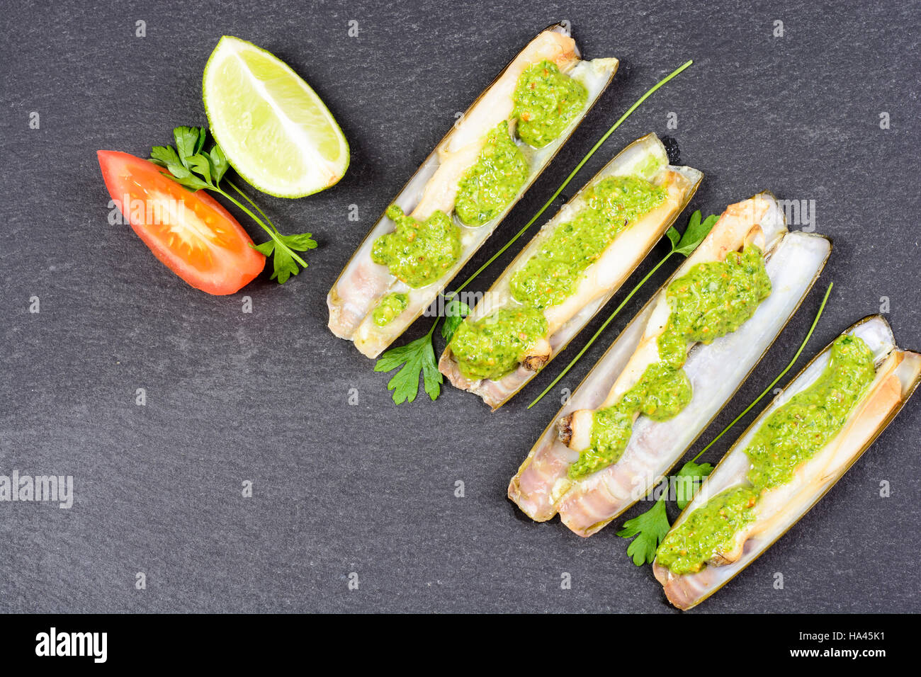 Razor clams navajas with green parsley pesto ona black slate plate ...