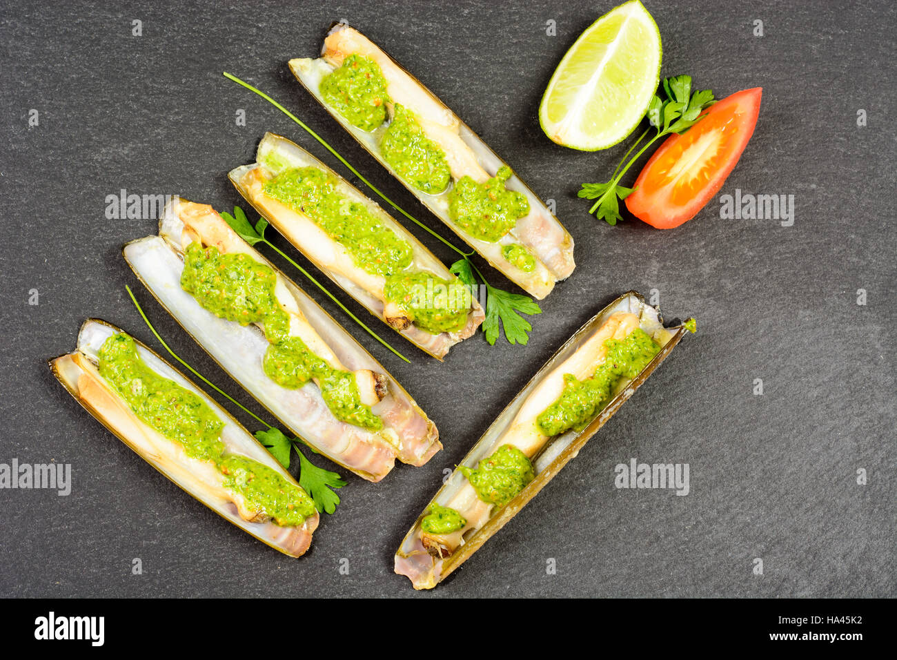 Razor clams navajas with green parsley pesto ona black slate plate ...
