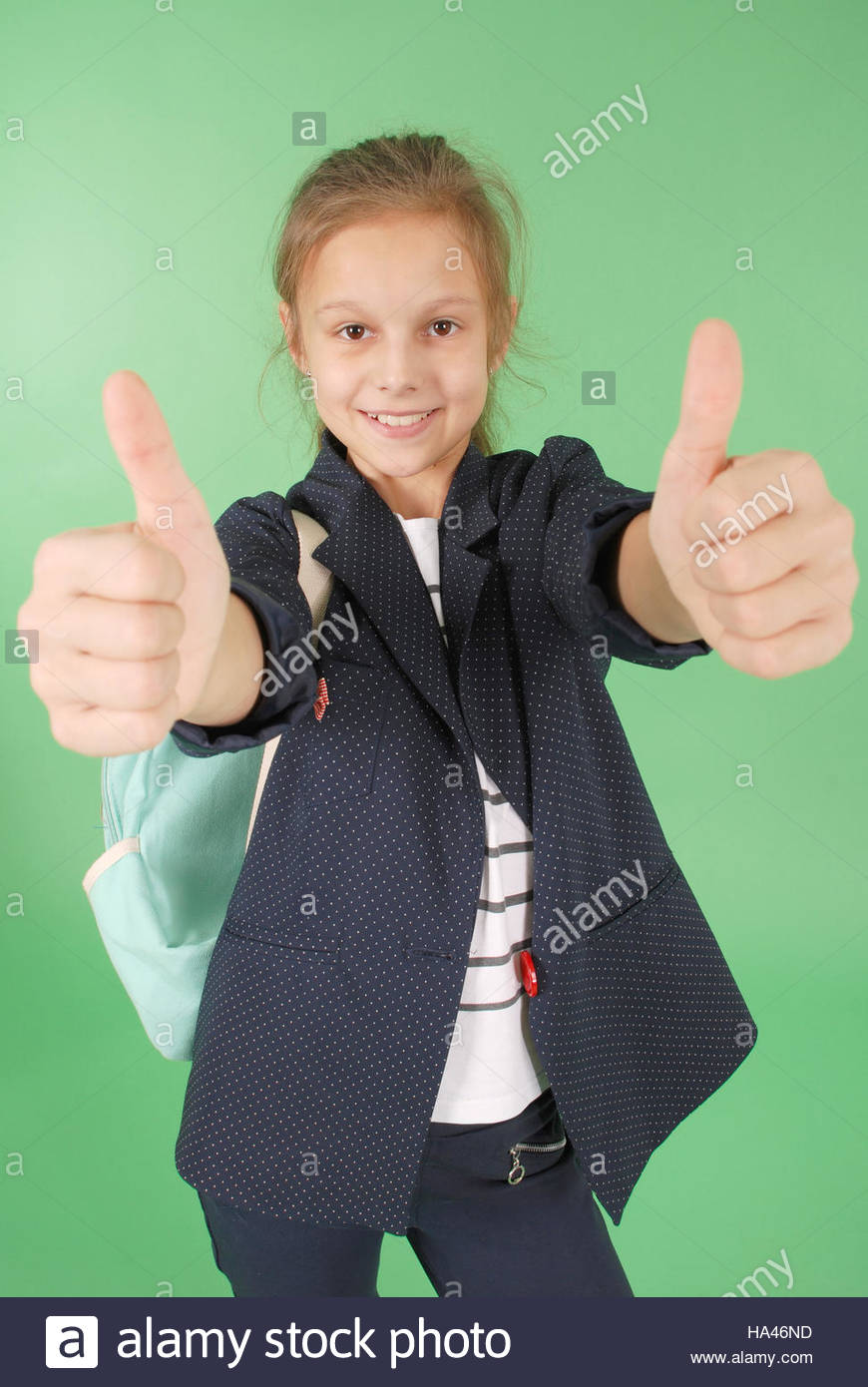 Smiling young school girl showing thumbs up isolated on green ...