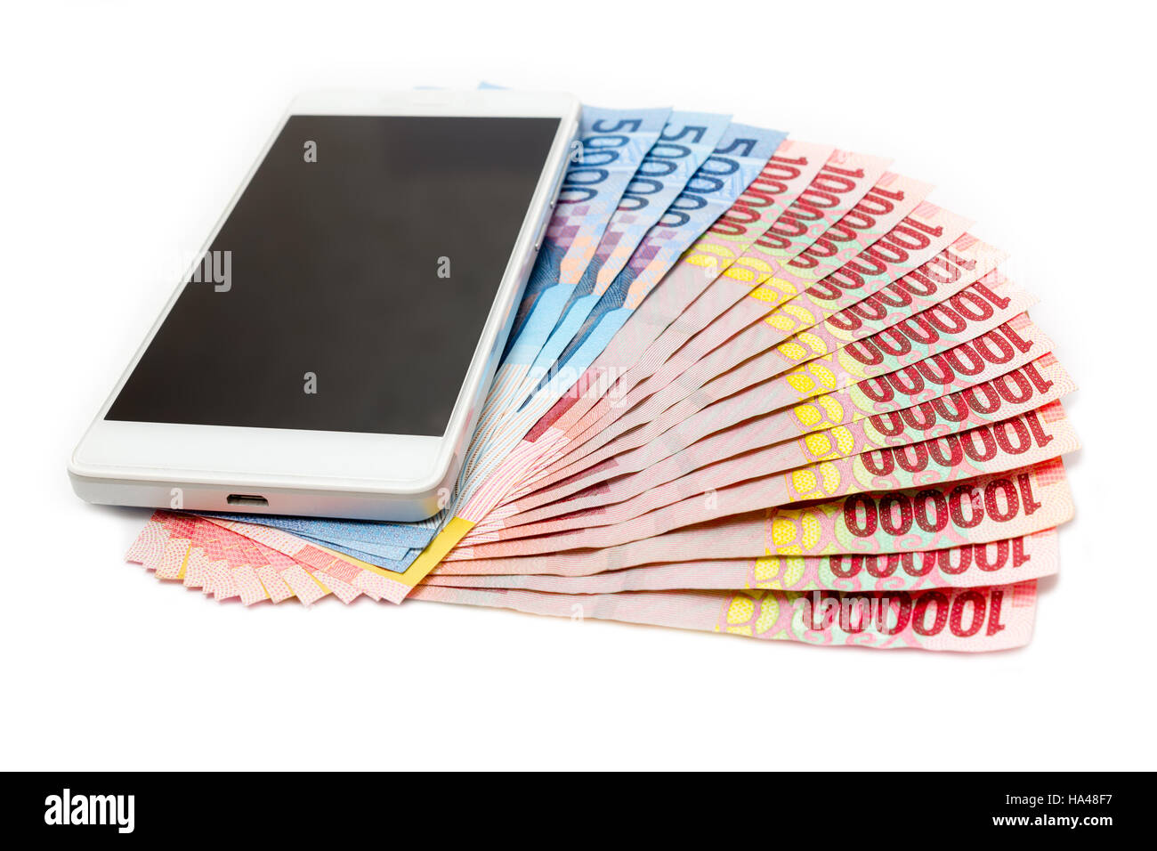 Smartphone above the piles of Indonesian Rupiah (IDR) banknotes on the ...