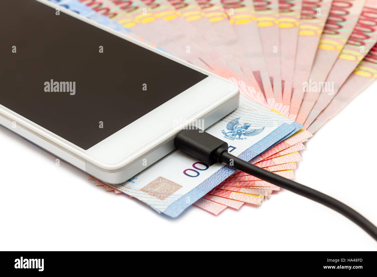Smartphone above the piles of Indonesian Rupiah (IDR) banknotes on the ...