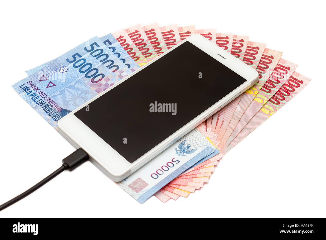 Smartphone above the piles of Indonesian Rupiah (IDR) banknotes on the ...
