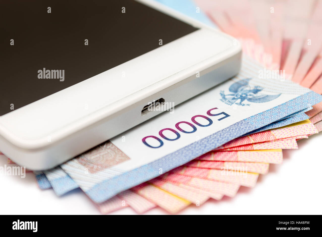 Smartphone above the piles of Indonesian Rupiah (IDR) banknotes on the ...
