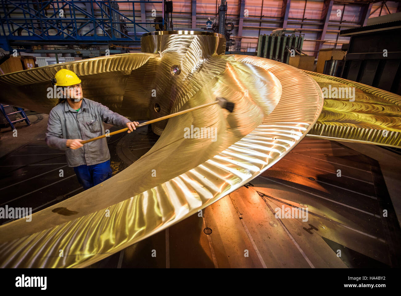A worker uses a broom to clean a ship propeller at the Metalguss Ltd ...