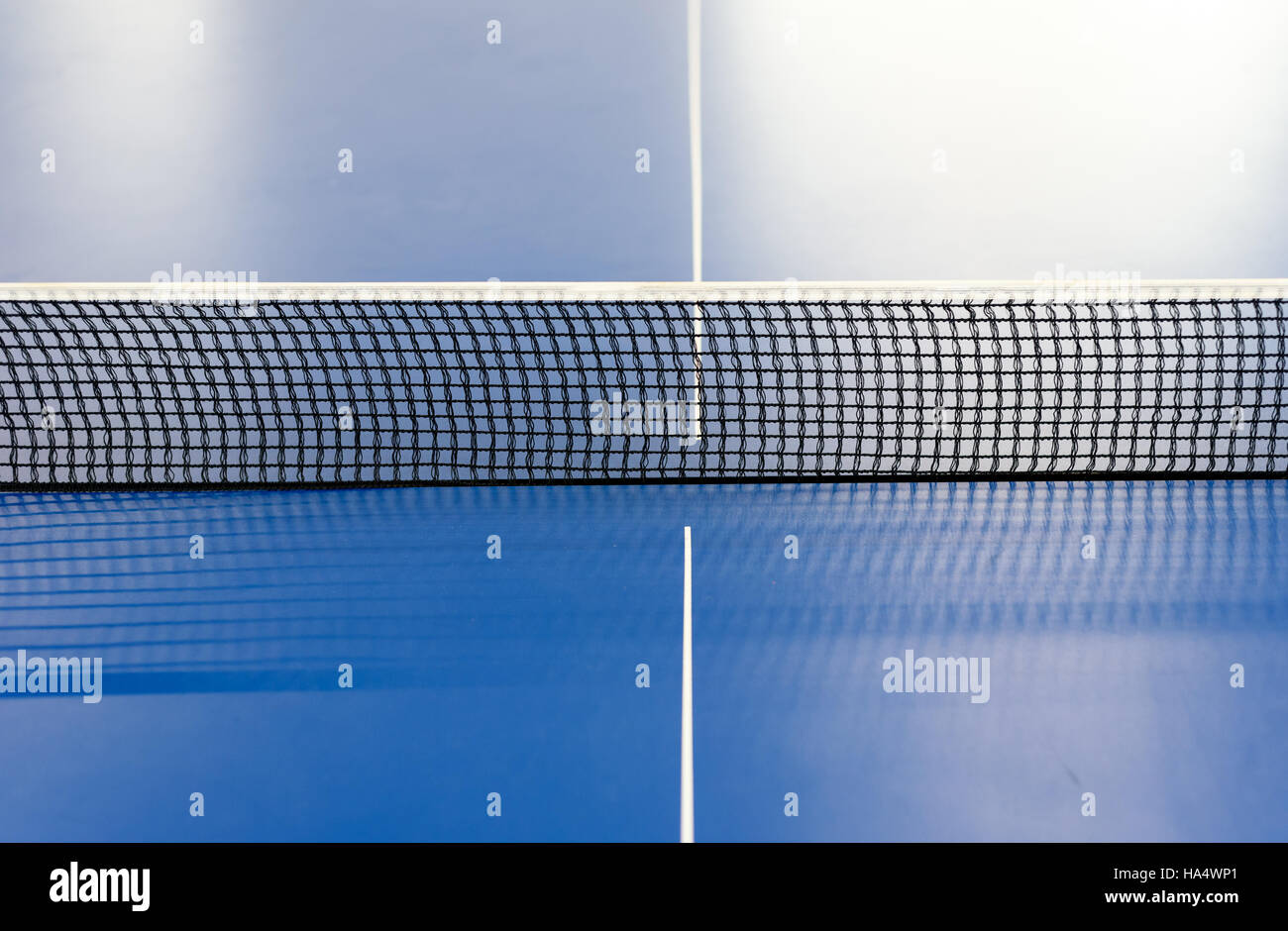 Horizontal table tennis net in black mesh dividing a blue colored ping ...