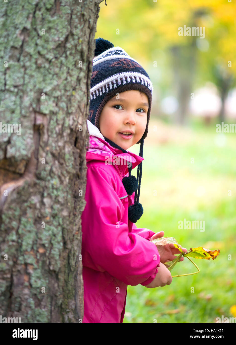 kid in autumn park hidden behind tree and smile Stock Photo - Alamy