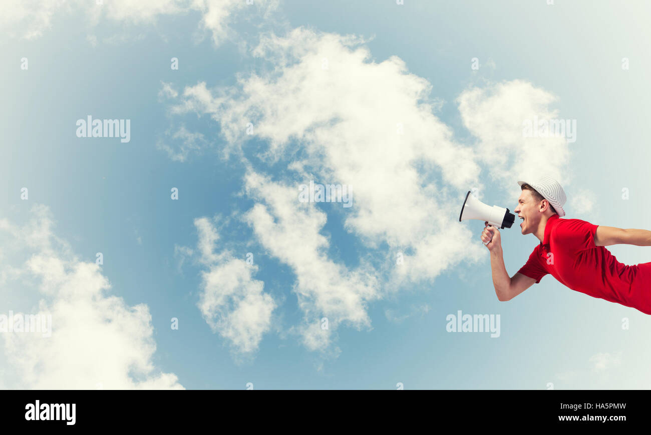 Young man shouting in megaphone with blue sky background Stock Photo ...