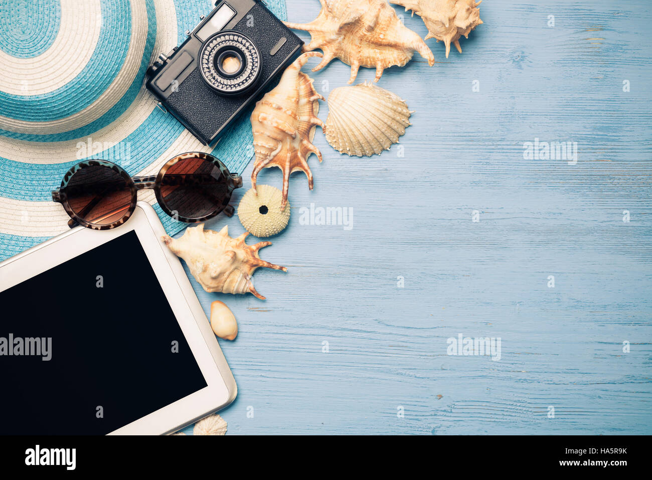 Straw hat sunglasses and photocamera among sea shells and stones on ...