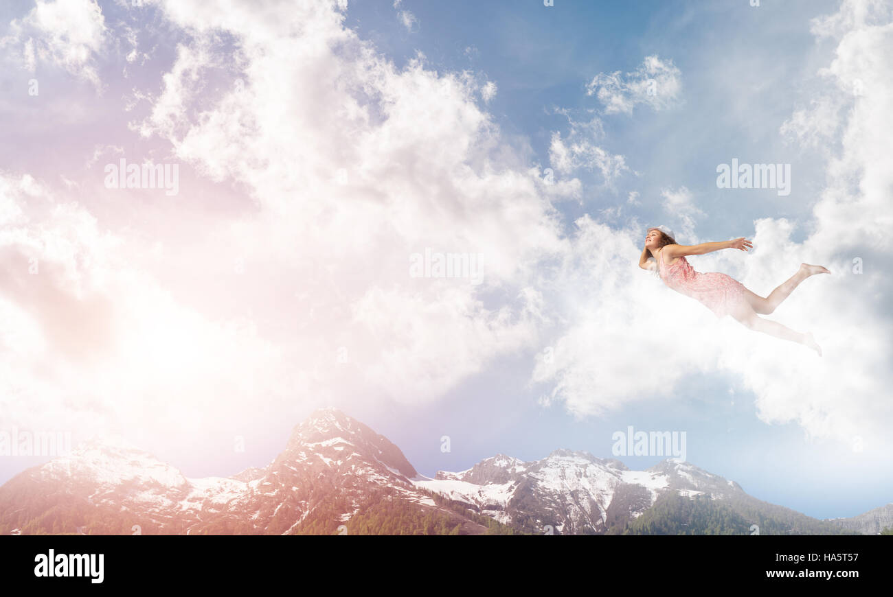 Young woman flying high in blue sky Stock Photo - Alamy