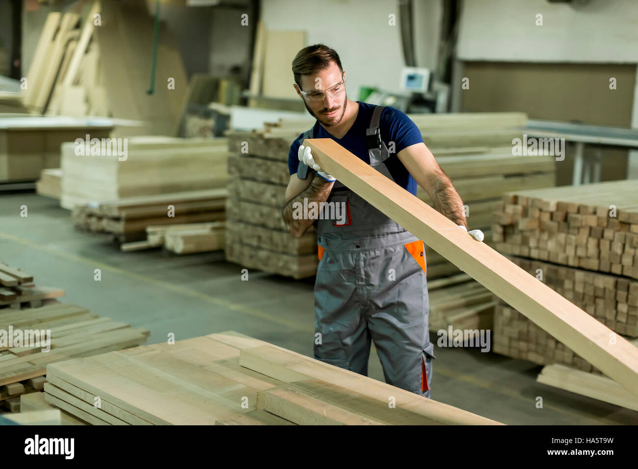 Young worker works in a factory for the production of furniture Stock ...