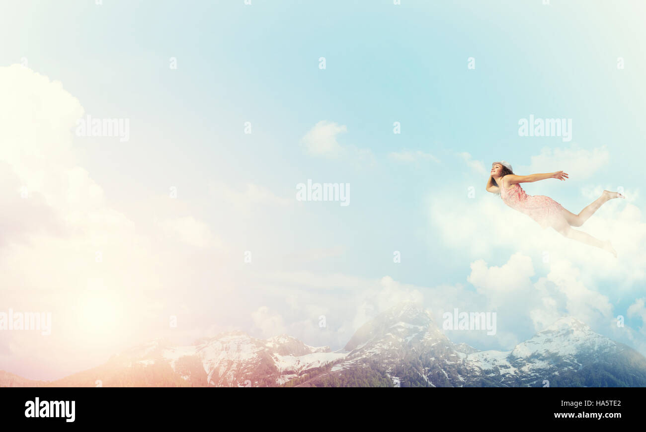 Young woman flying high in blue sky Stock Photo - Alamy