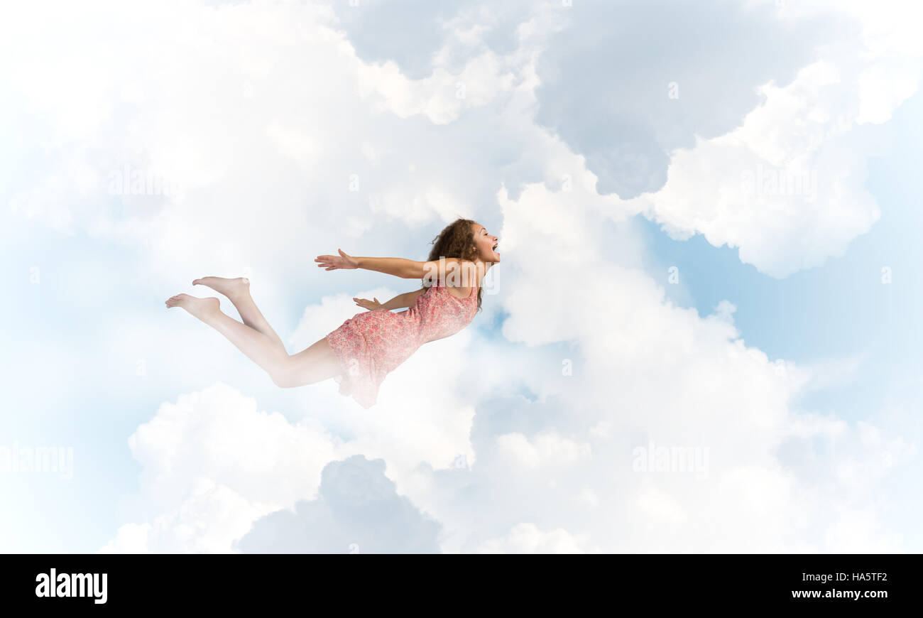Young woman flying high in blue sky Stock Photo - Alamy