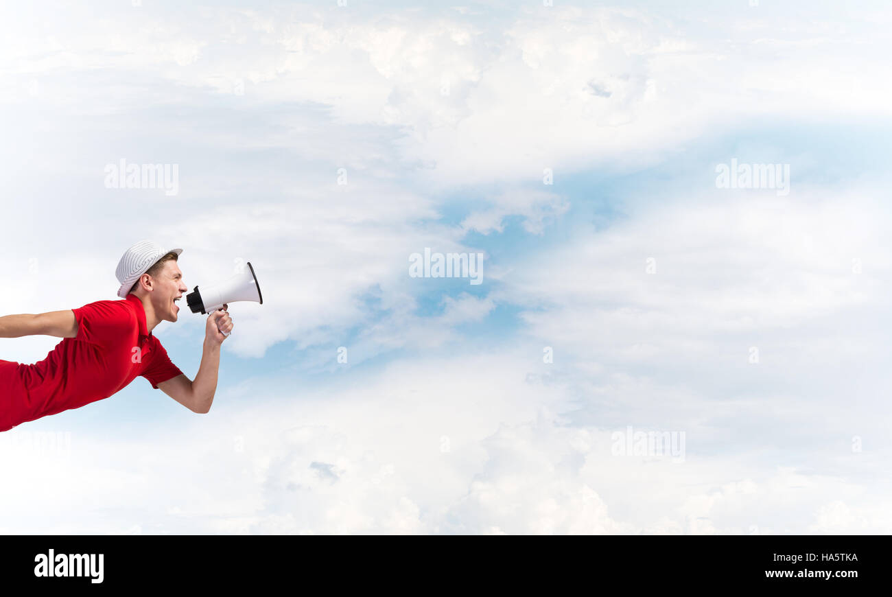 Young man shouting in megaphone with blue sky background Stock Photo ...