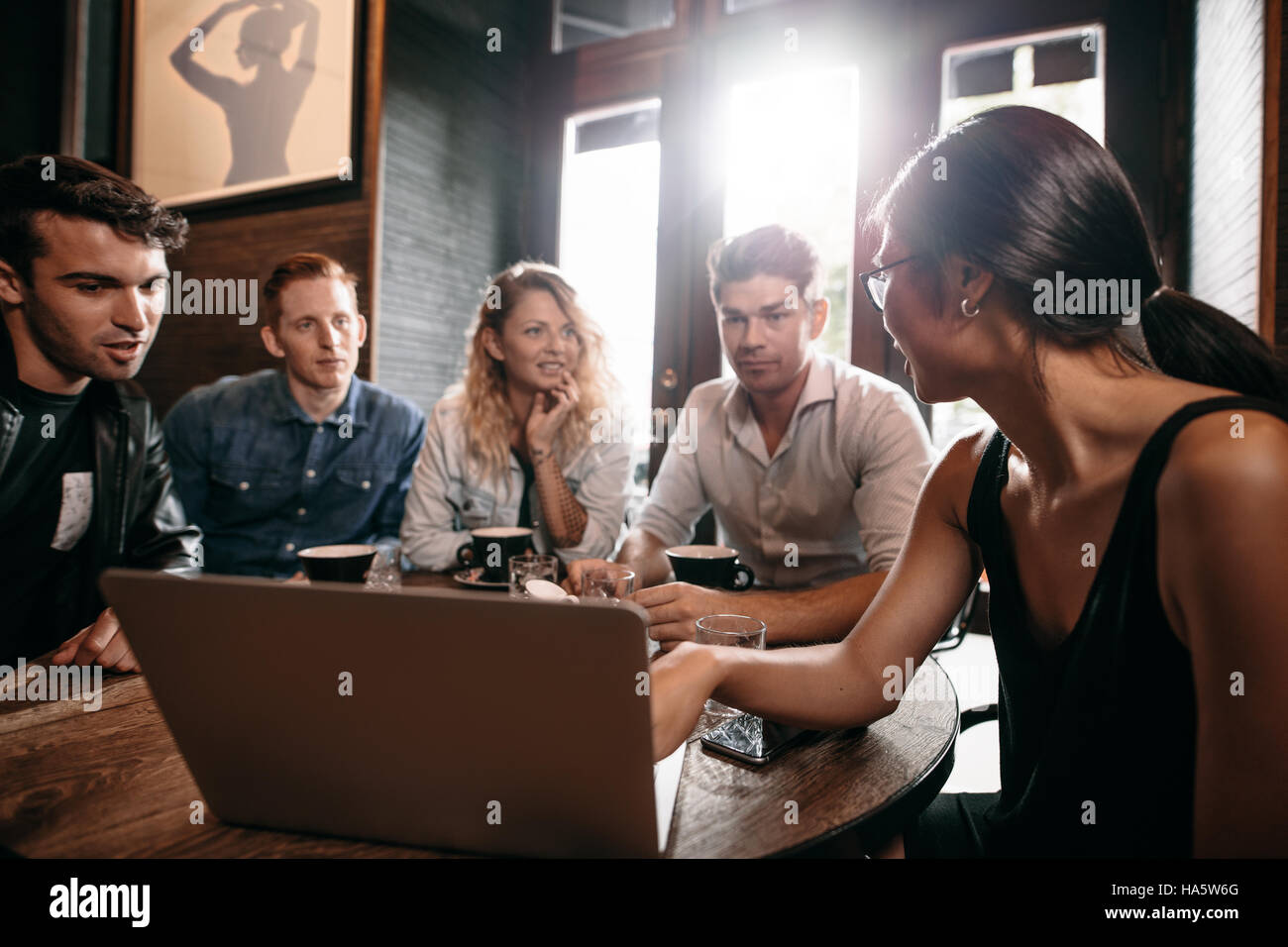 Smiling friends spending their time in coffee shop and discussing ...