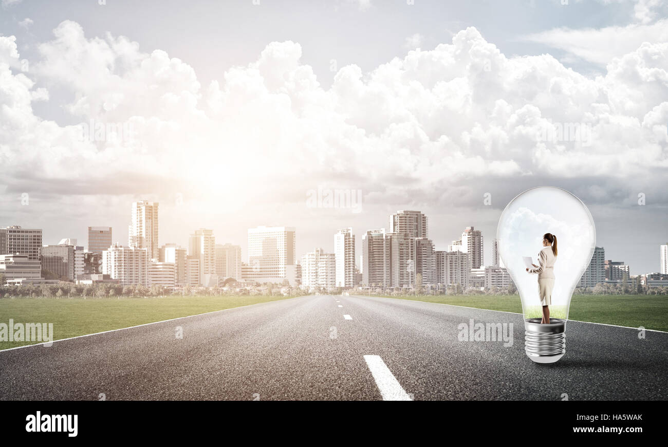 Young businesswoman trapped inside of light bulb on asphalt road Stock ...