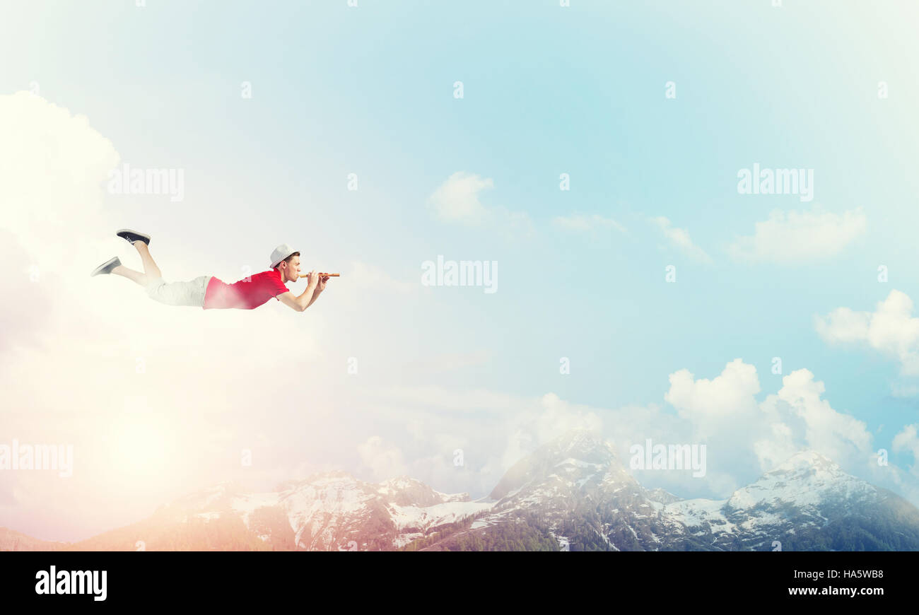 Young cheerful man flying high in sky and playing fife Stock Photo - Alamy