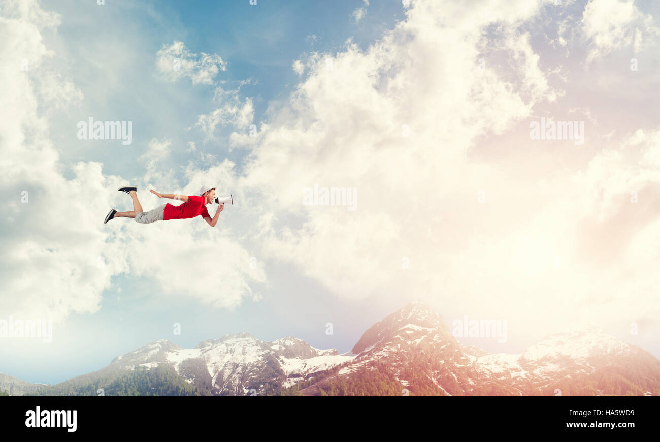 Young cheerful man with megaphone flying high in sky Stock Photo - Alamy