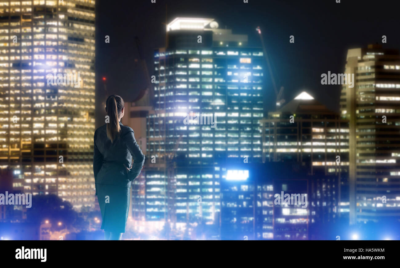 Rear view of elegant businesswoman viewing lights of night city Stock ...