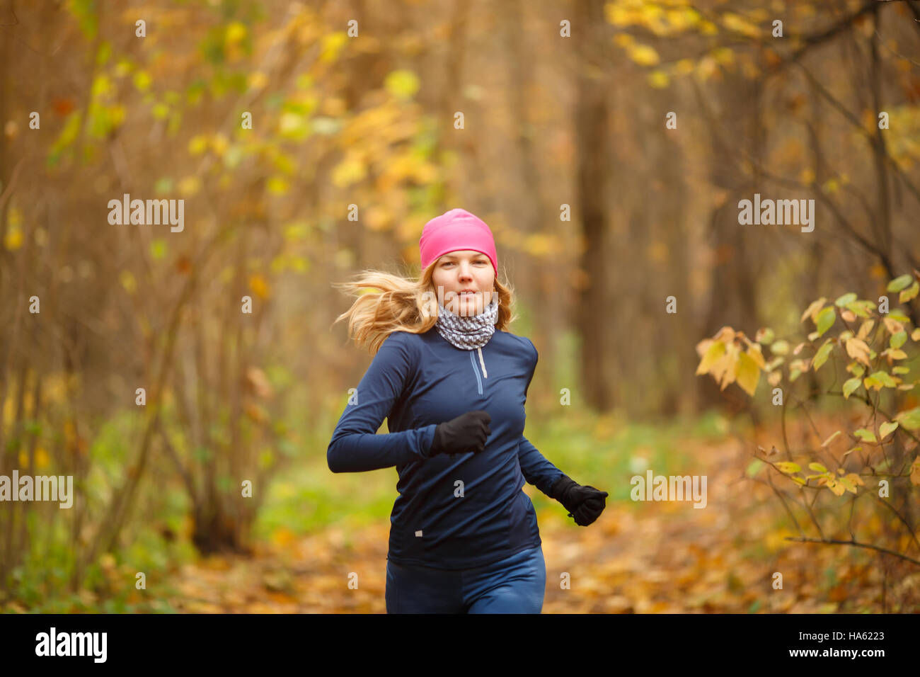 Young female athlete with long blonde hair in sports suit running in ...