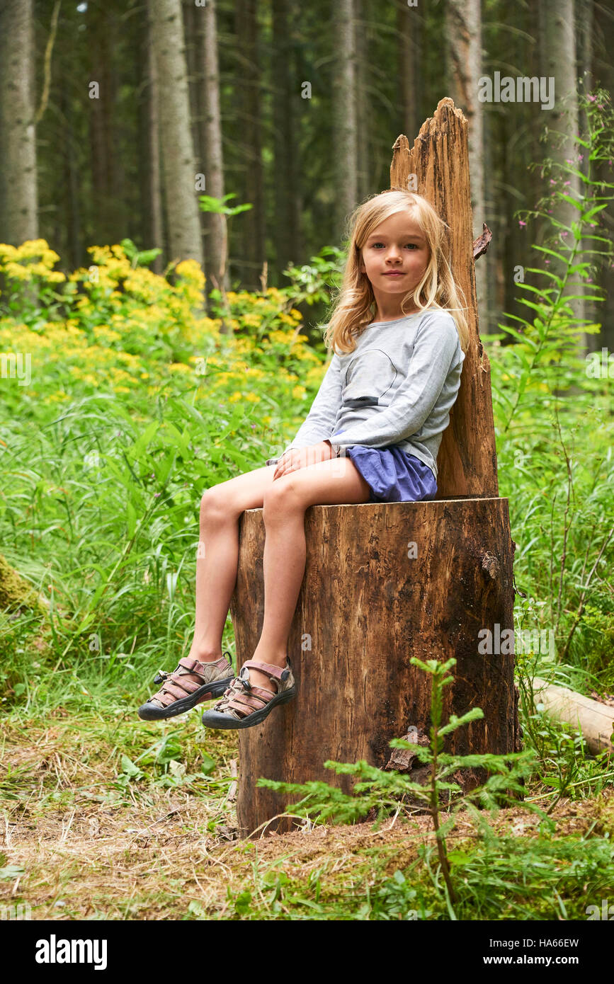 Little child cute girl sitting on a tree stump (looks like a throne) in ...