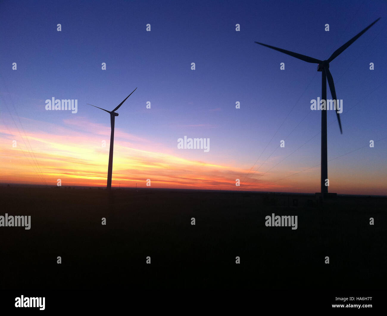 A beautiful sunrise over a field of wind turbines, symbolizing the ...