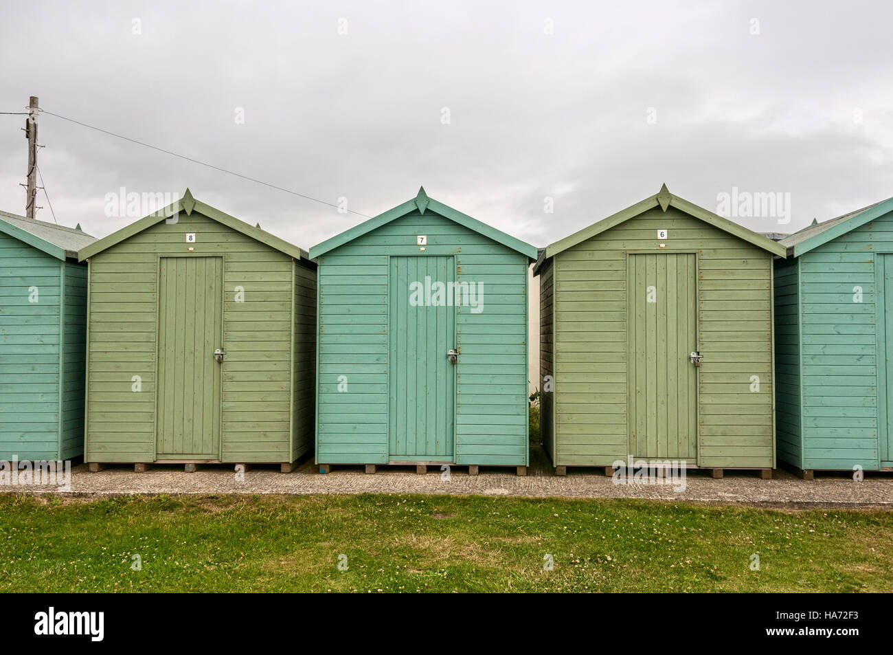 A row of beach huts sitting on the top edge of the beach are protected ...