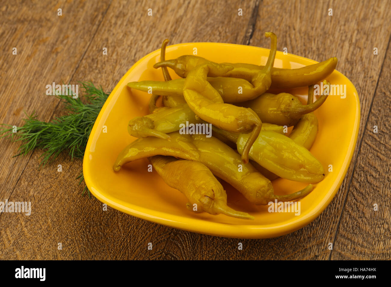 Pickled green pepperoni pepper in the bowl on wood background Stock ...