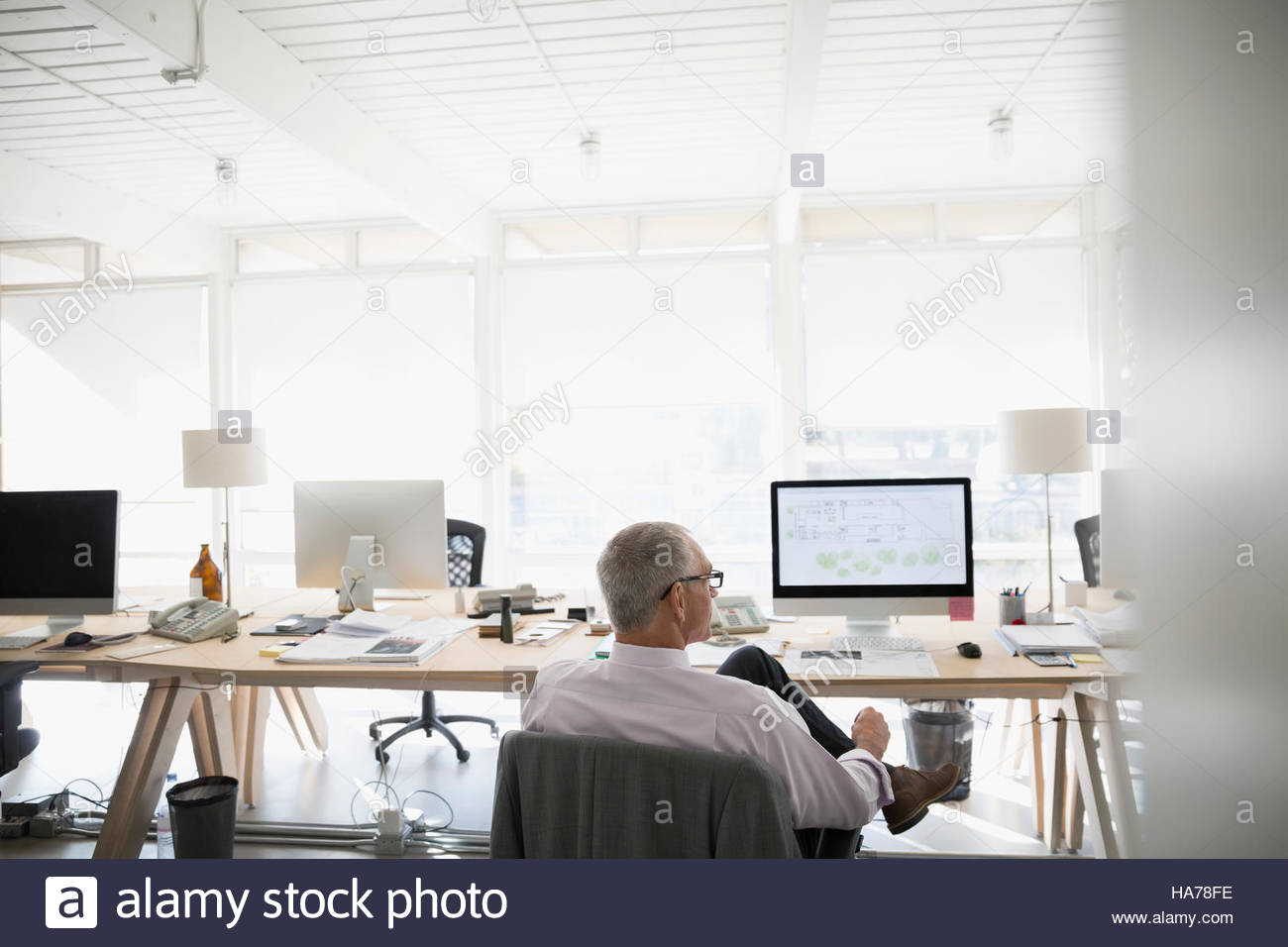 Male architect working at computer with digital blueprint in office ...