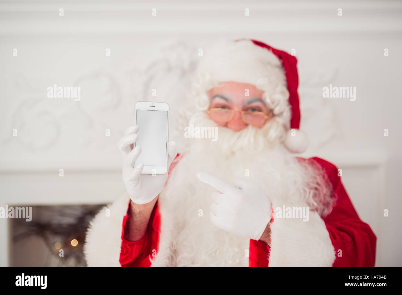 Santa Claus shows a smartphone against red background Stock Photo - Alamy