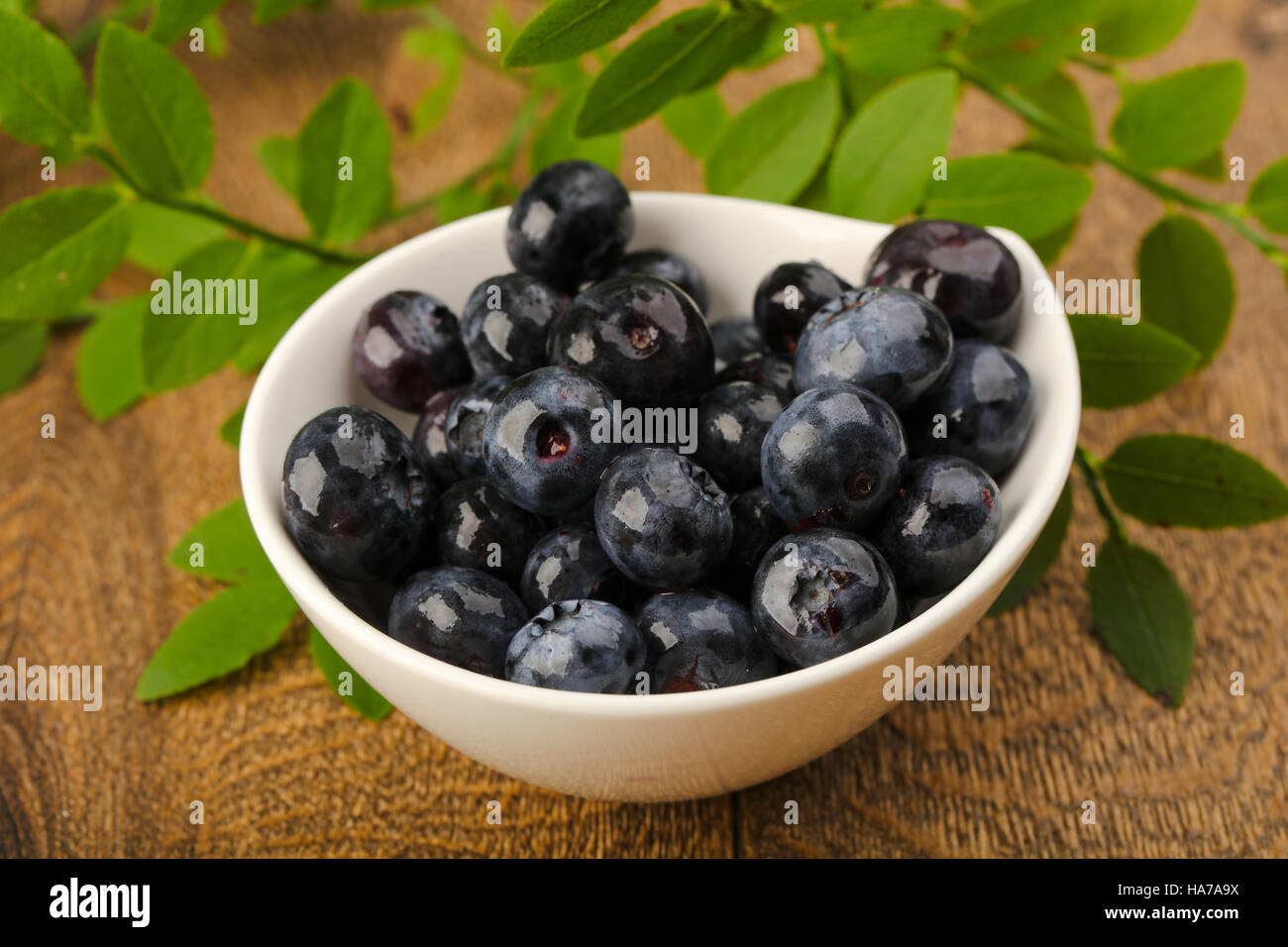 Ripe Blueberry heap with leaves on wood background Stock Photo - Alamy