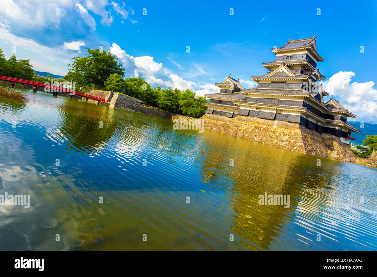 Tilted view of Matsumoto Castle, red bridge and moat water reflection ...