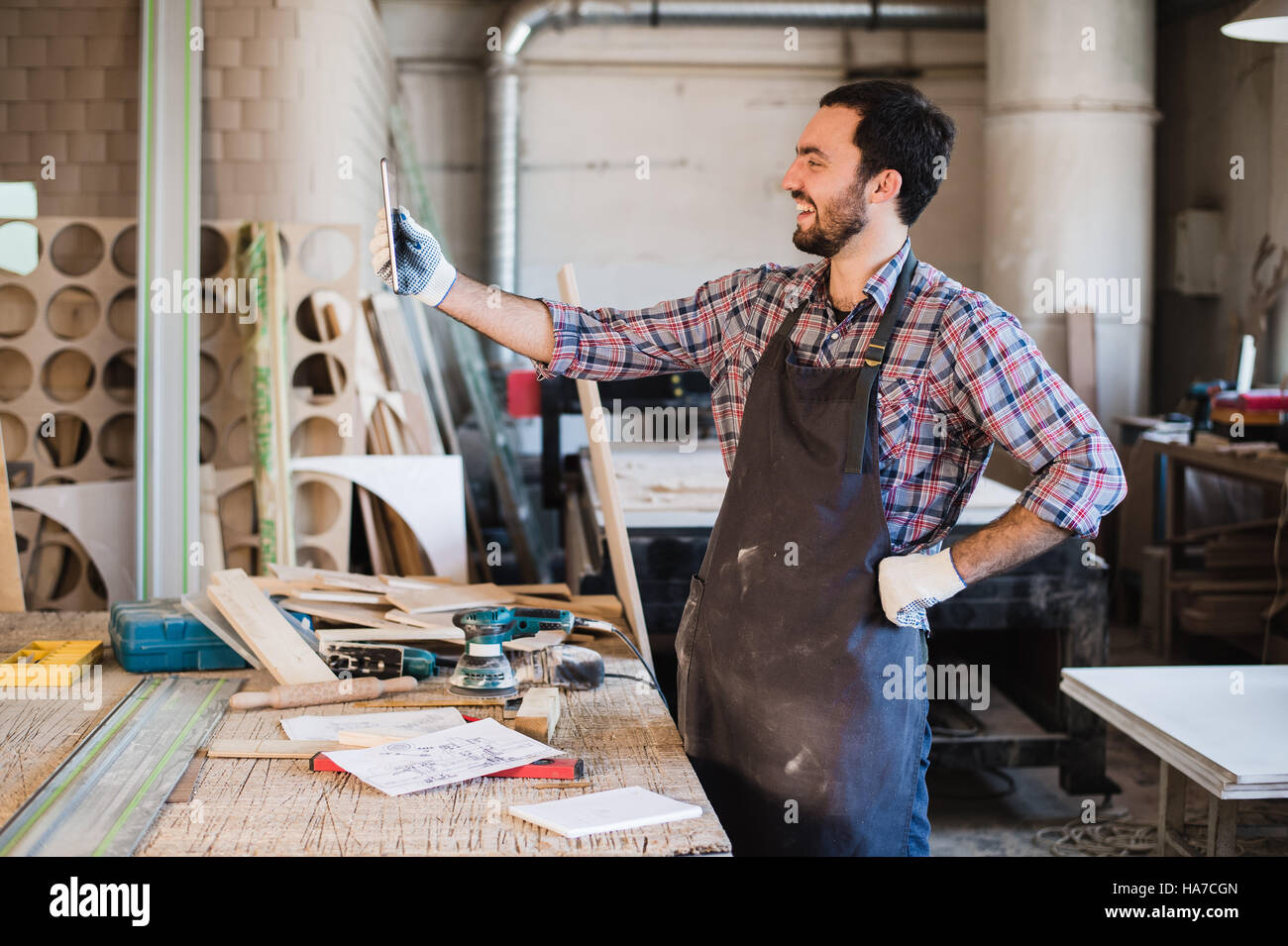 Portrait of a carpenter standing in his woodwork studio and holding ...