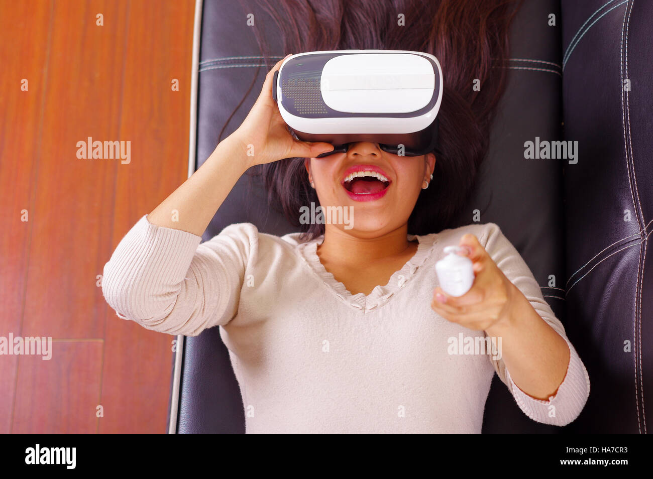 Young brunette woman lying down wearing virtual reality goggles ...