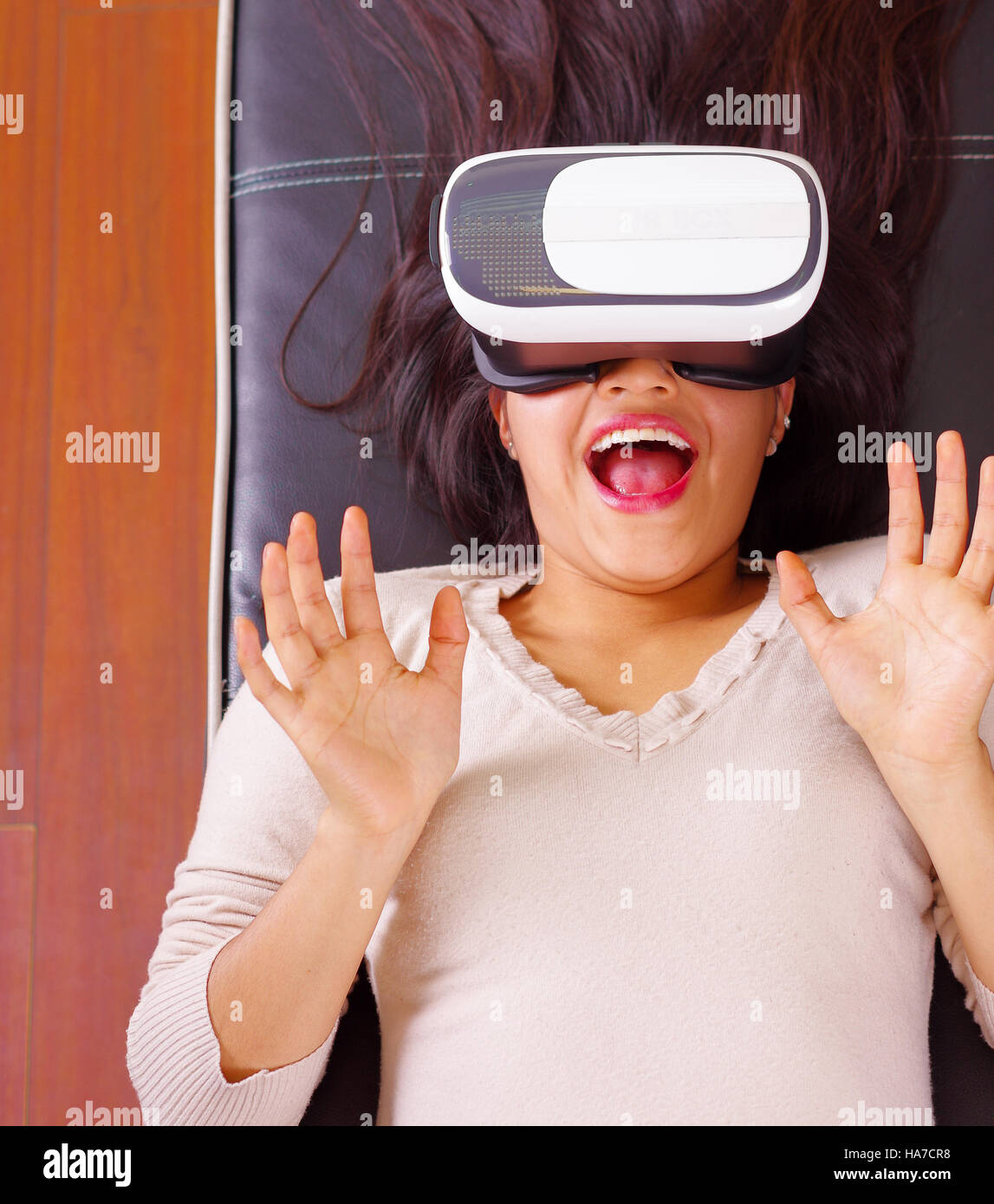 Young brunette woman lying down wearing virtual reality goggles ...
