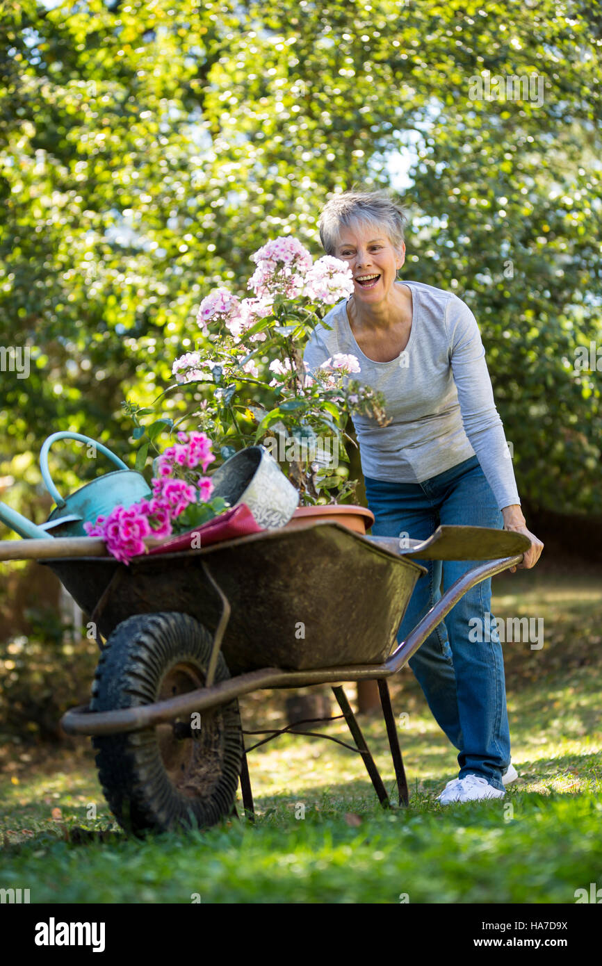 Senior woman pushing wheelbarrow in garden Stock Photo - Alamy