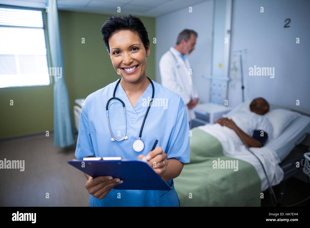 Portrait of female nurse writing on clipboard in ward Stock Photo - Alamy