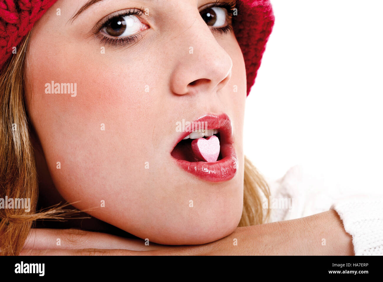 Young woman with red woolen hat eating heart-shaped candy Stock Photo ...