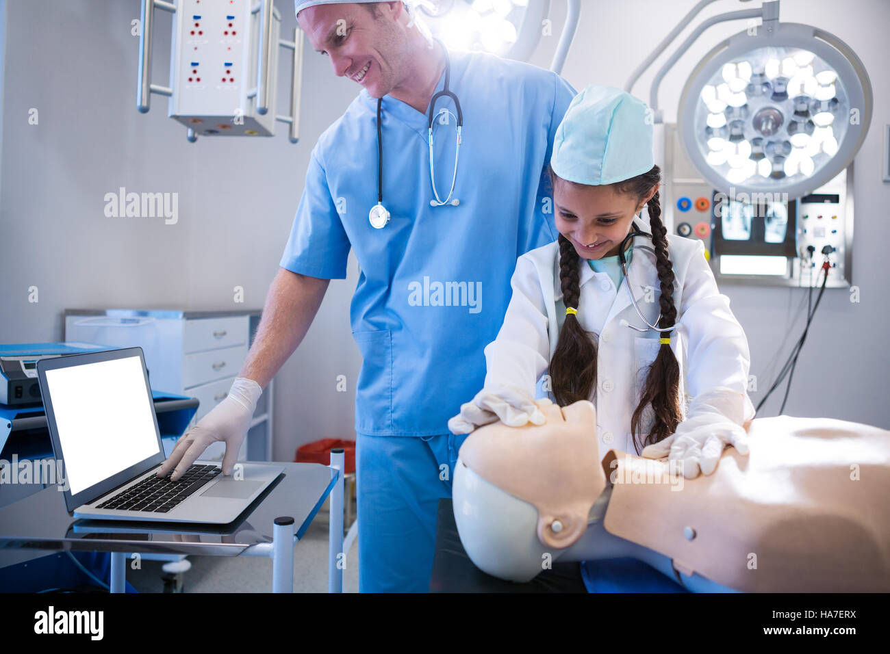 Doctor using laptop while girl examining a dummy Stock Photo - Alamy
