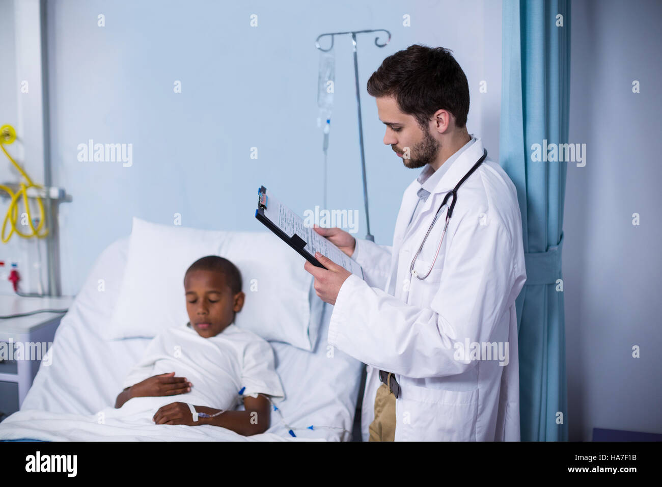 Doctor looking at report while patient sleeping on bed Stock Photo - Alamy