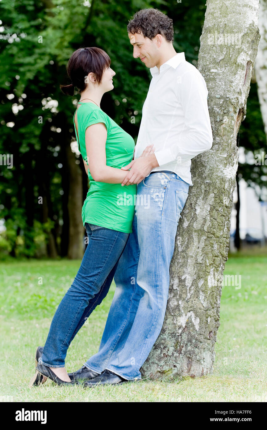 Pair in love leaning against a tree Stock Photo - Alamy